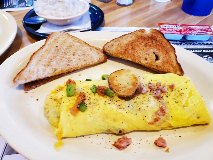 An omelet that puts hotel breakfast buffets to shame – fluffy eggs cradling savory fillings with toast standing by for the inevitable cleanup duty.