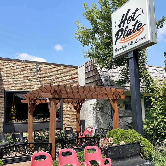 The Hot Plate sign stands tall against Minnesota skies, promising breakfast bliss within. That wooden pergola frames the entrance like a portal to a more delicious dimension.