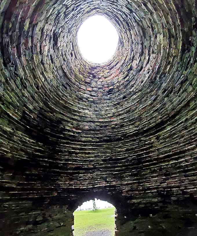 Looking skyward from inside a charcoal kiln reveals perfect stonework craftsmanship &ndash; industrial architecture with cathedral-like precision.