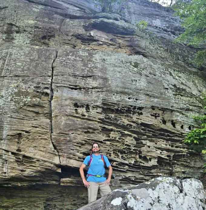 Standing triumphant against ancient rock walls, this hiker embodies the perfect scale of human ambition against nature's grand canvas.