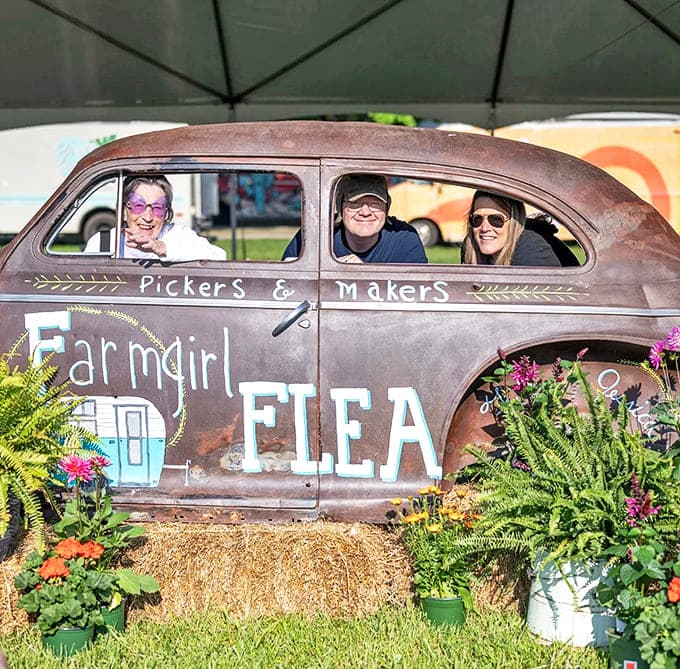 Old Car Photobooth: An upcycled vintage car serves as both market mascot and photo opportunity, its weathered exterior now painted with the Farmgirl Flea logo.