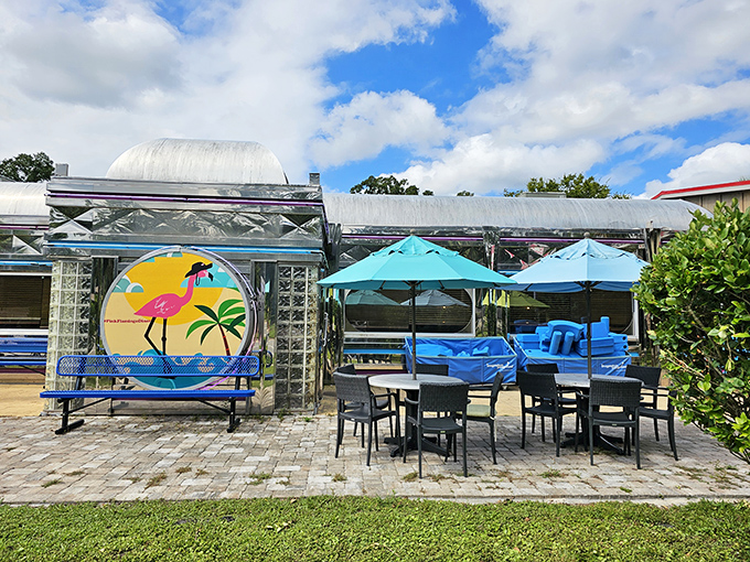 Turquoise umbrellas shade outdoor tables where diners can enjoy Florida sunshine with their meals, creating a resort-like oasis of relaxation.