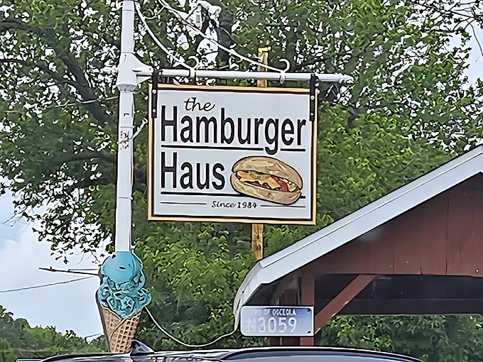 The classic Hamburger Haus sign swings proudly above the roadside, its retro design and illustrated burger announcing a longtime local favorite serving up simple comfort classics since 1984.