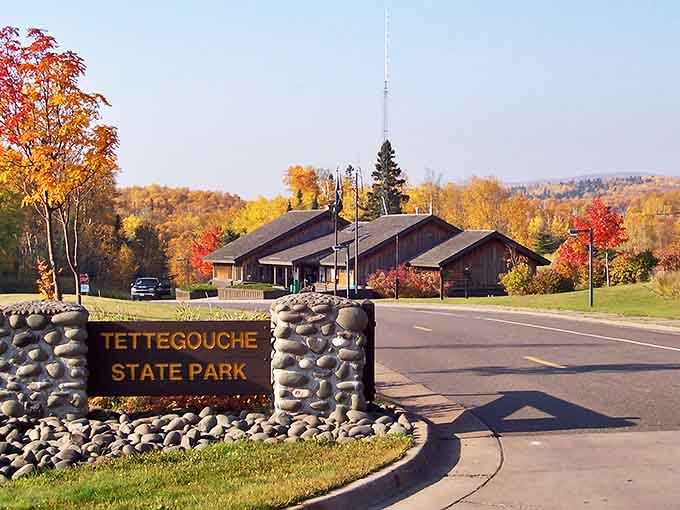 Your adventure starts here: Tettegouche's welcoming sign stands amid autumn splendor, promising wilderness wonders just beyond the parking lot.