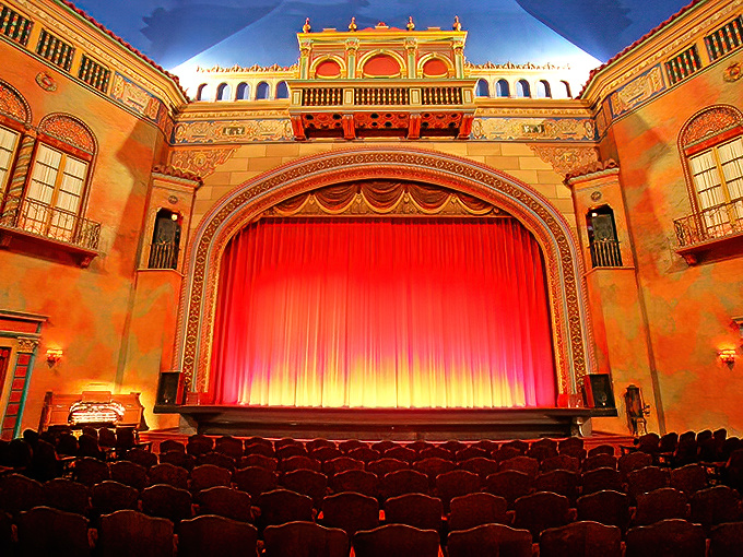 The stage awaits beneath a ceiling painted to resemble a Mediterranean sky, the red curtain promising wonders that no streaming service can duplicate.