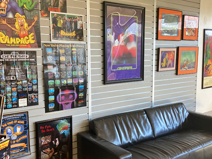 Gaming history lines these walls, each framed poster and cabinet art a window into the visual language that shaped our collective imagination.