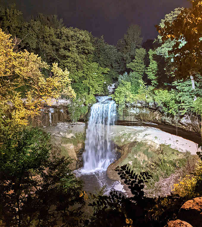 Even after the sun goes down, the illuminated falls offer a serene and glowing landscape under the dark evening sky.