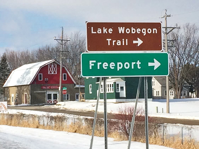 Winter transforms the Lake Wobegon Trail into a snowy paradise, with directional signs pointing visitors toward Freeport's warm welcome.