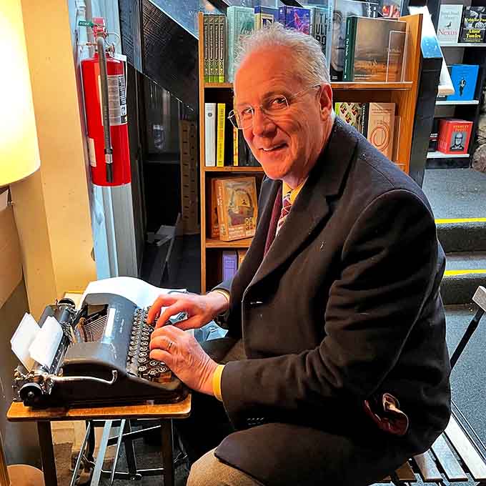 A visitor types away on the public typewriter, contributing to the ongoing collaborative story of Literati and its literary pilgrims.