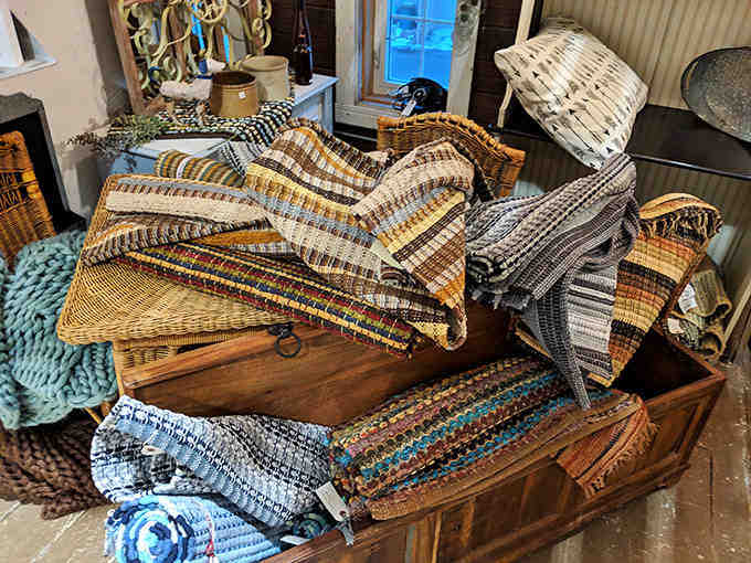 A treasure chest overflows with handwoven rag rugs, each representing hours of careful work transforming scraps into practical art for humble farmhouse floors.