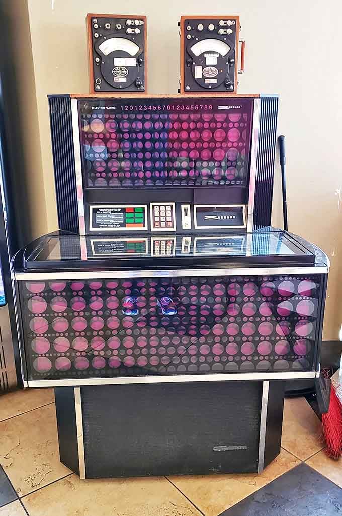 The jukebox stands sentinel, a gleaming guardian of musical memories ready to soundtrack your meal with hits from simpler times.