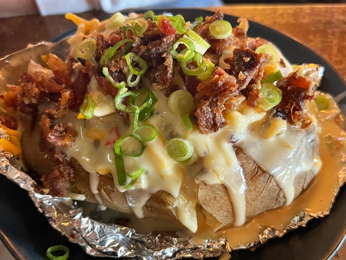 This loaded baked potato transforms the humble spud into a canvas for barbecue creativity, topped with melted cheese and green onions.