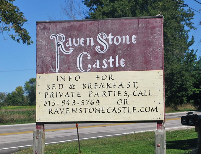 The weathered sign stands as a humble herald for the magnificent structure beyond, inviting travelers to experience a slice of medieval magic in the Midwest.