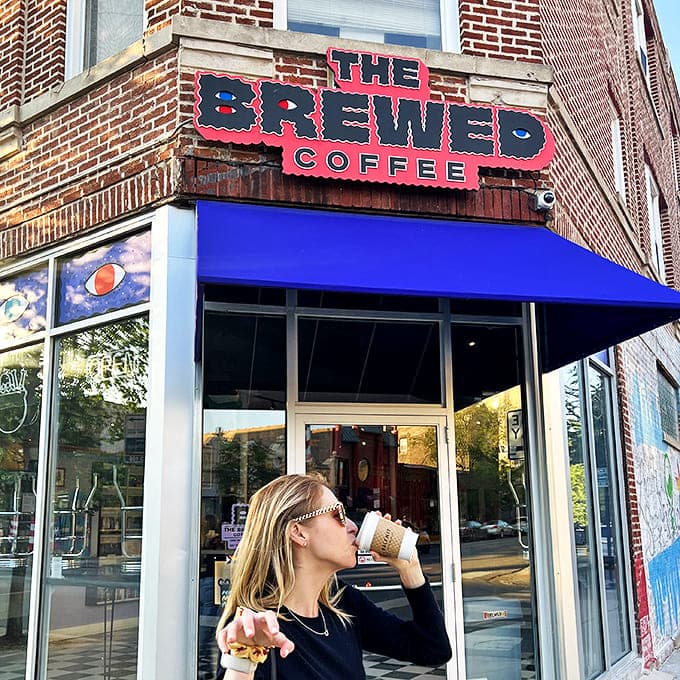A customer enjoys the perfect combination&mdash;iced coffee and a sweet treat&mdash;beneath the iconic red sign that beckons horror fans and coffee lovers alike.