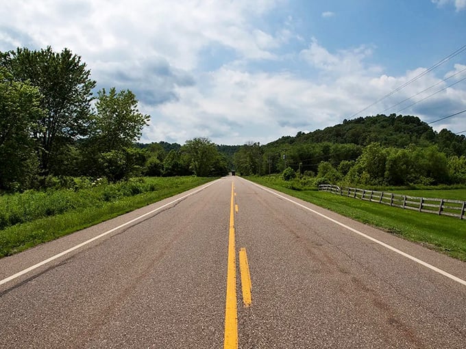 The open road beckons in Cincinnati, where yellow lines stretch toward rolling hills and blue skies promise adventure around every curve.