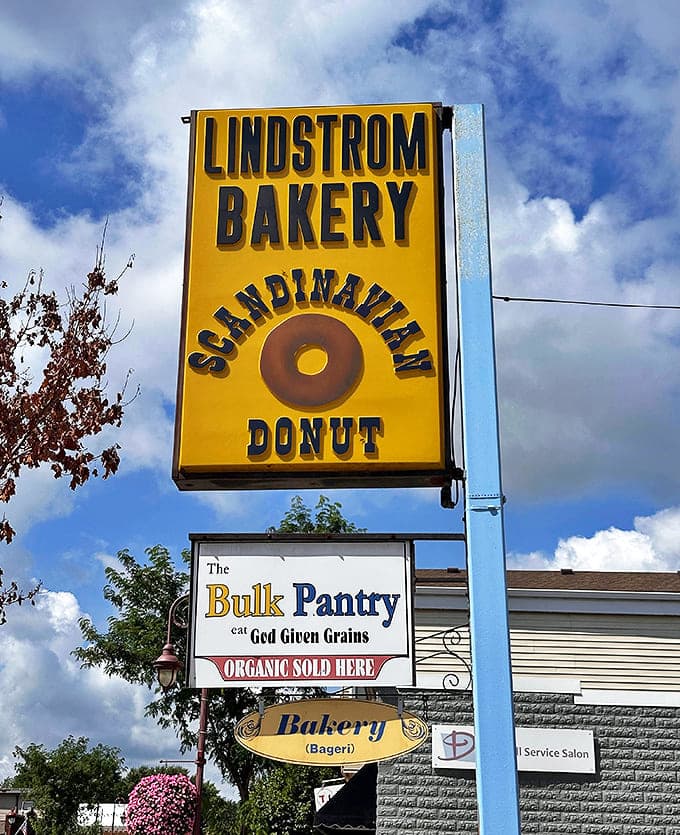 The iconic yellow sign of Lindstr&ouml;m Bakery stands tall against Minnesota's blue sky, a beacon for donut lovers seeking that perfect Scandinavian treat.
