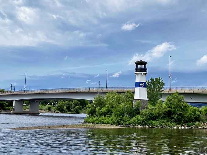 The classic blue and white lighthouse creates a striking contrast against the modern bridge, blending history with contemporary city life.