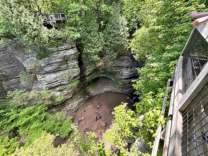 Looking down into nature's amphitheater where visitors gather like tiny actors on a grand geological stage carved over millennia.