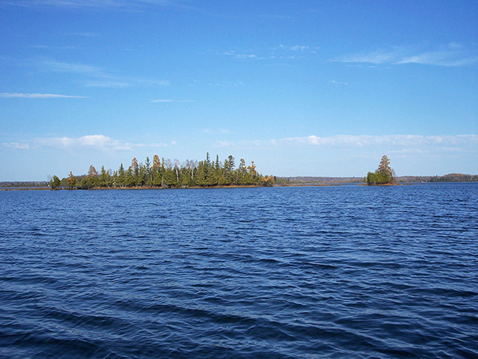 The horizon melts into blue infinity where Deer Lake's pristine waters meet Minnesota's expansive sky, creating nature's perfect dividing line.