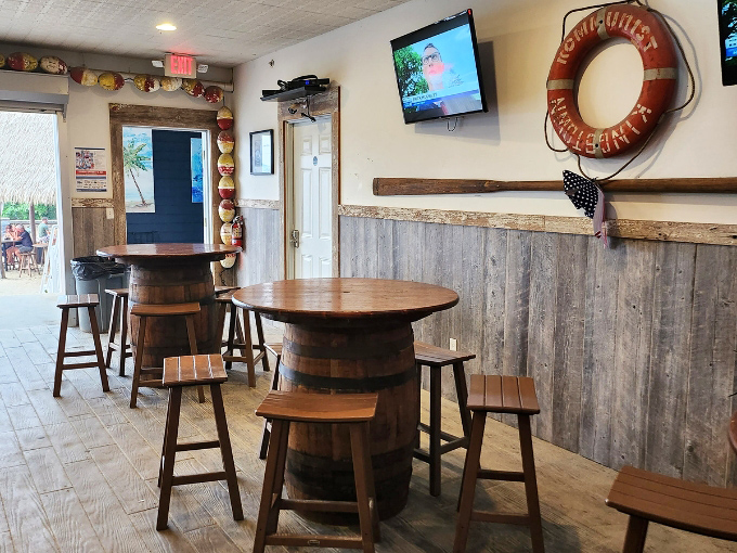 Barrel tables and weathered wood paneling create that "I've discovered a secret rum runner's hideaway" feeling that makes every drink taste better.