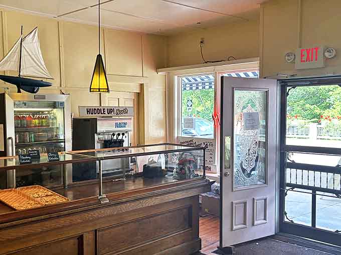 Vintage wooden display cases and warm yellow walls create the perfect backdrop for pastry magic, while a model sailboat nods to nearby Grand Traverse Bay.