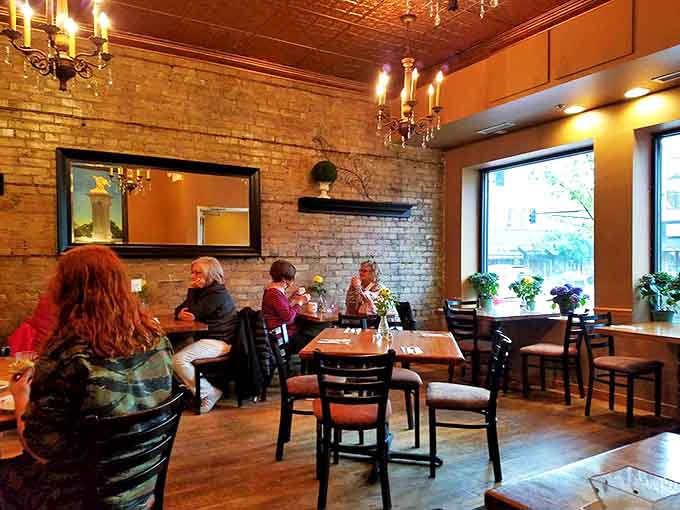 Exposed brick walls meet elegant chandeliers in this cozy interior where dessert dreams and casual conversations flourish equally well.