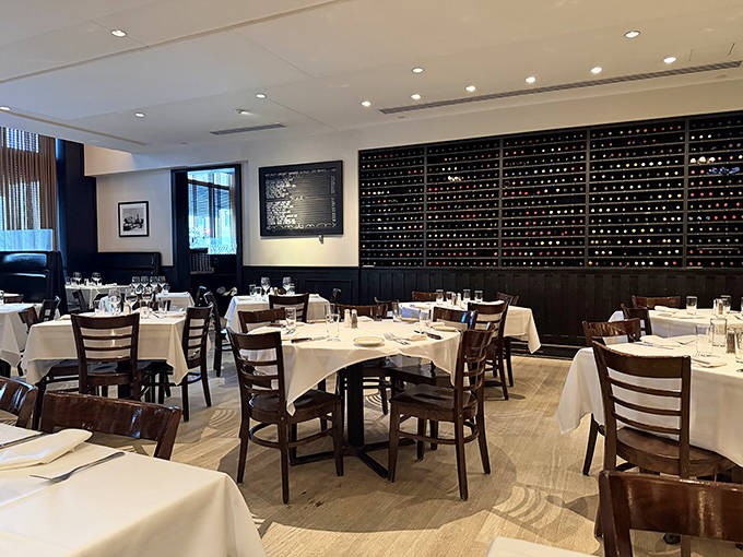 White tablecloths, dark wood, and that impressive wine wall &ndash; dining room elegance that says "serious steak business happens here."