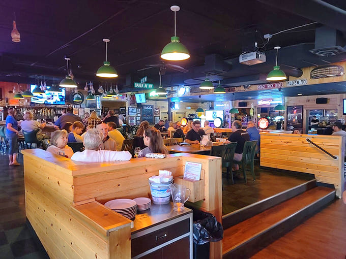 Wooden booths, green pendant lights, and walls adorned with memorabilia create that perfect neighborhood bar atmosphere where everyone feels at home.