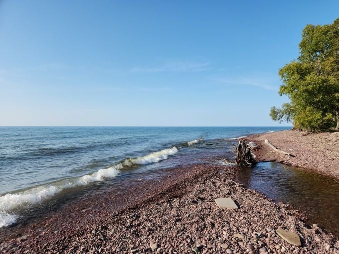 The shoreline stretches like nature's own treasure chest, with smooth stones in every hue imaginable waiting for the curious explorer.
