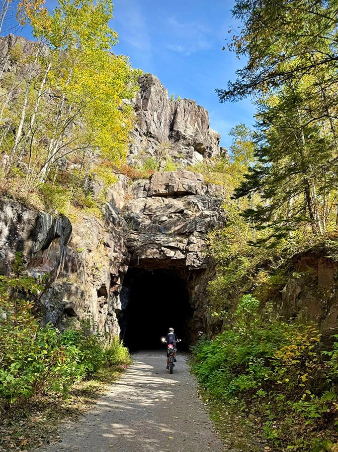A cyclist approaches the stone portal, where industrial history and wilderness create the perfect dramatic backdrop for exploration.