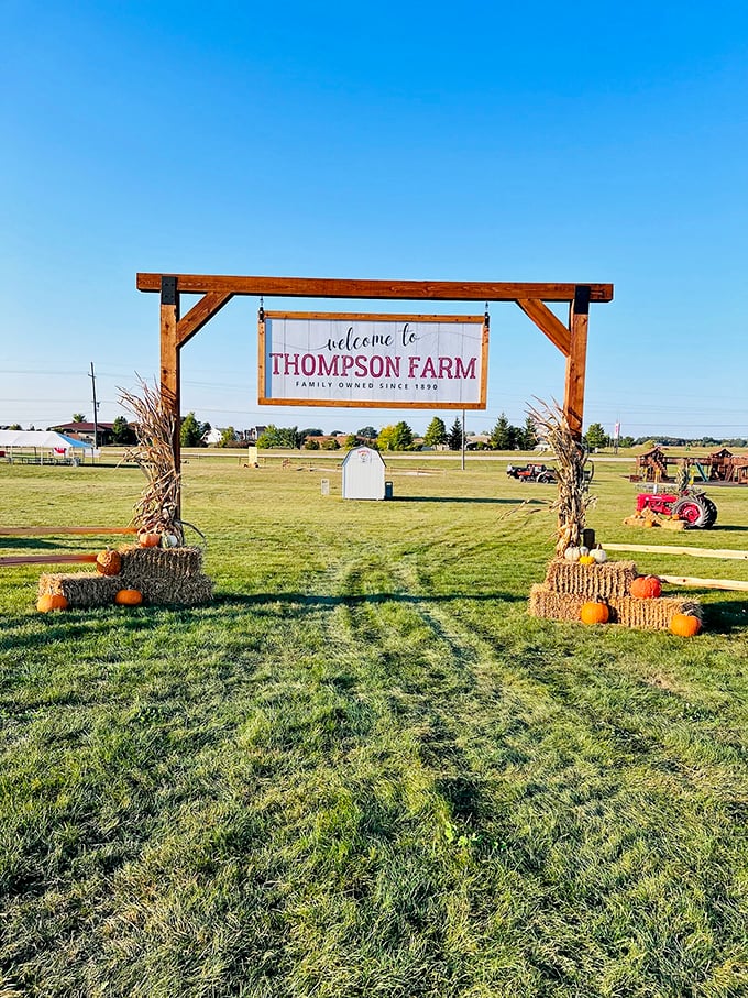 Welcome home! Thompson Farm's rustic entrance sign, framed by hay bales and pumpkins, promises authentic country charm beyond the gate.