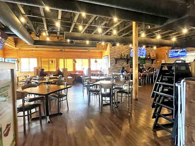 Warm wood tones and exposed industrial elements create the perfect backdrop for game day gatherings or casual dining experiences.