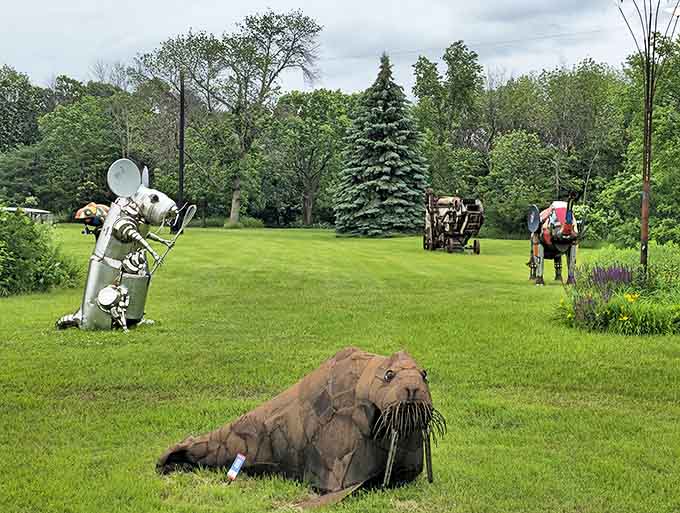 Metal figures frozen in mid-action populate the grassy landscape, creating a surreal playground where imagination runs wild among repurposed materials.