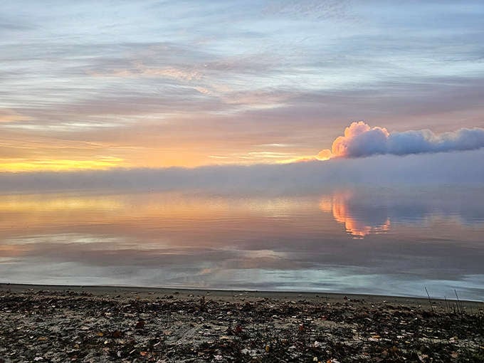 Dawn breaks over Higgins Lake, painting the sky in pastels that reflect perfectly on water so still it could be glass.
