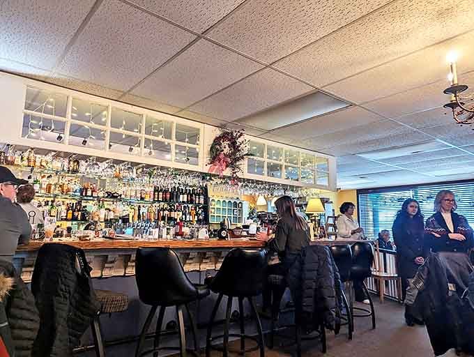 The well-stocked bar area buzzes with activity as patrons gather for conversation and libations in this cozy community hub.