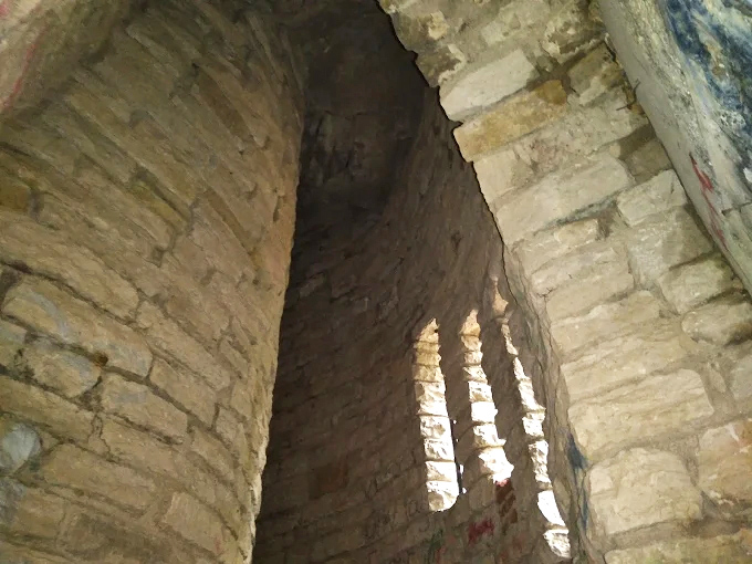 Peek inside the tower's interior, where sunlight filters through narrow openings, creating dramatic shadows on ancient stone.