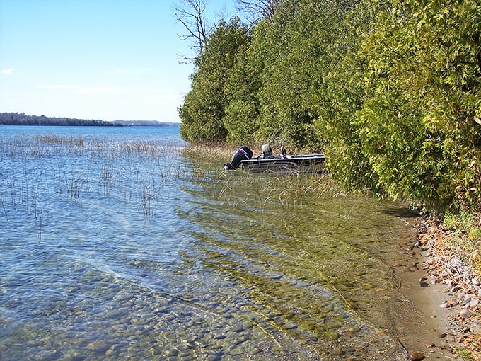 Crystal clear shallows reveal Deer Lake's secrets &ndash; smooth stones and gentle ripples invite exploration from passing anglers.