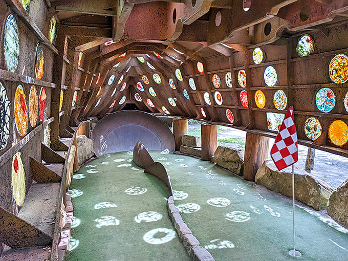 Inside the "Holey Ship," circular stained glass windows create a cathedral-like atmosphere that elevates mini golf to an almost spiritual experience.