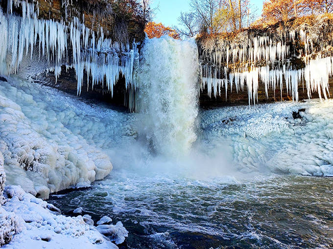 Witness a breathtaking winter wonderland as the cascading water transforms into a shimmering wall of ice and delicate, frozen icicles.