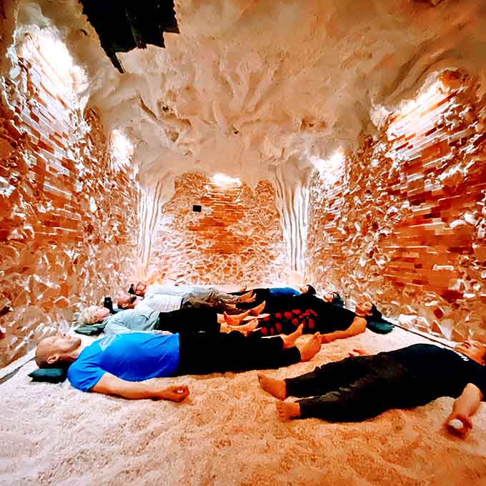 Visitors surrender to relaxation on zero-gravity chairs, looking like peaceful astronauts floating in a sea of pink salt.
