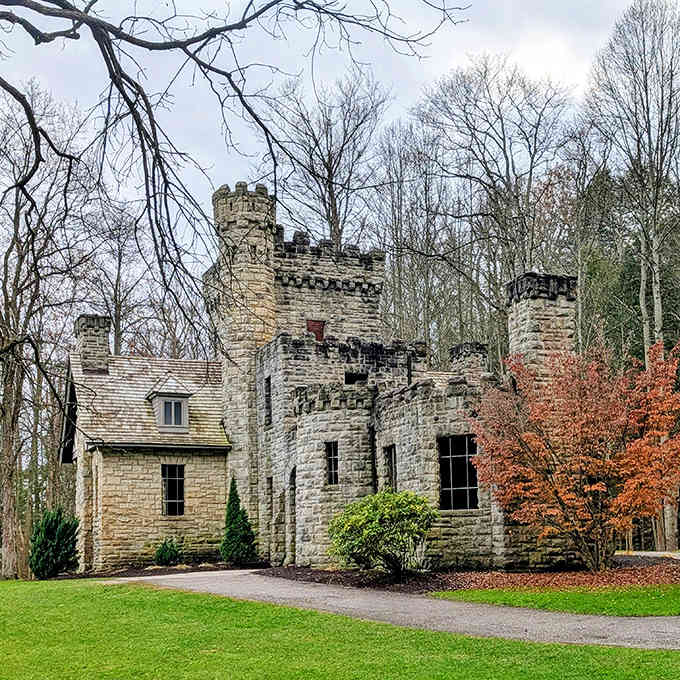 The castle's exterior showcases exquisite stonework that has weathered over a century, standing proud against the backdrop of lush trees.