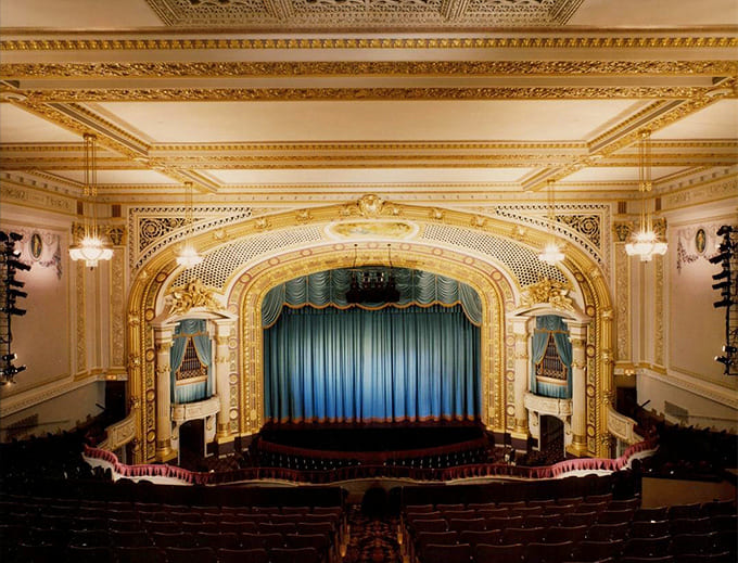The ornate proscenium arch frames the stage like a gilded picture frame, turning every performance into a masterpiece before it even begins.