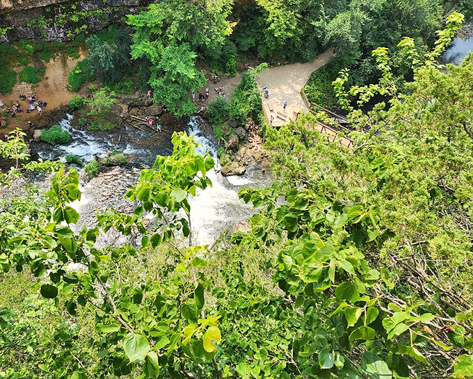 From above, visitors gather near the falls, their tiny figures highlighting the impressive scale of this natural amphitheater.