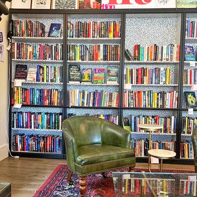 A reader's paradise awaits with blue-speckled shelving showcasing colorful spines, while a green leather chair invites hours of literary escape.
