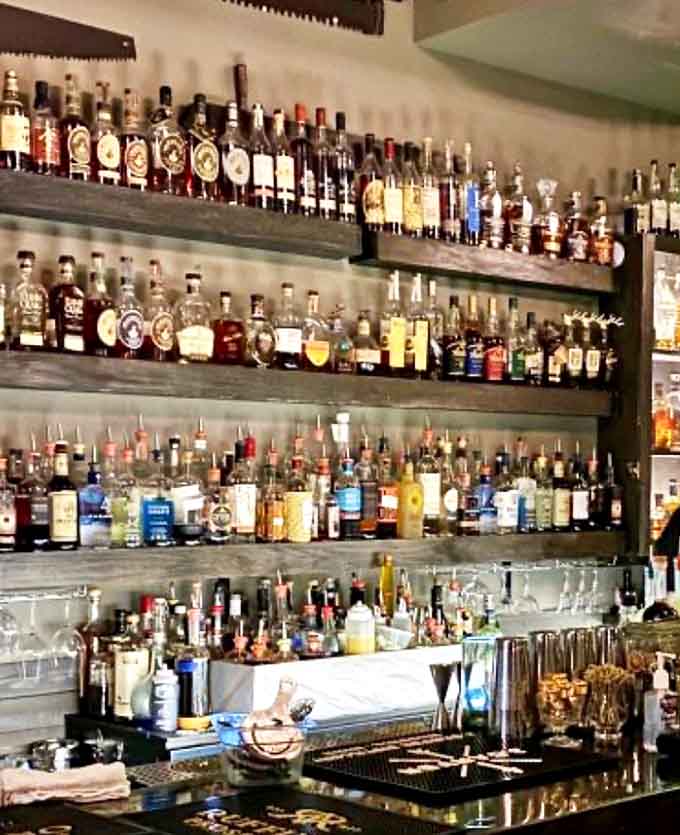 Liquid history on display &ndash; Shelves lined with amber treasures and crystal-clear spirits create a magnificent backdrop for the mixology magic that unfolds nightly.