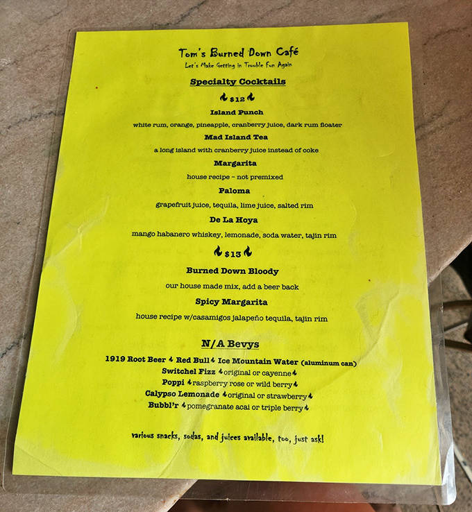 The vibrant yellow menu promises liquid adventures with cheeky offerings like "Let's Make Getting In Trouble Fun Again" cocktails.