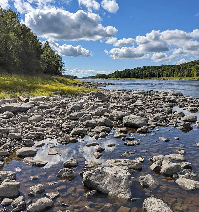 Ancient rocks tell billion-year-old stories along the shore, where clear waters reveal colorful stones beneath the surface.