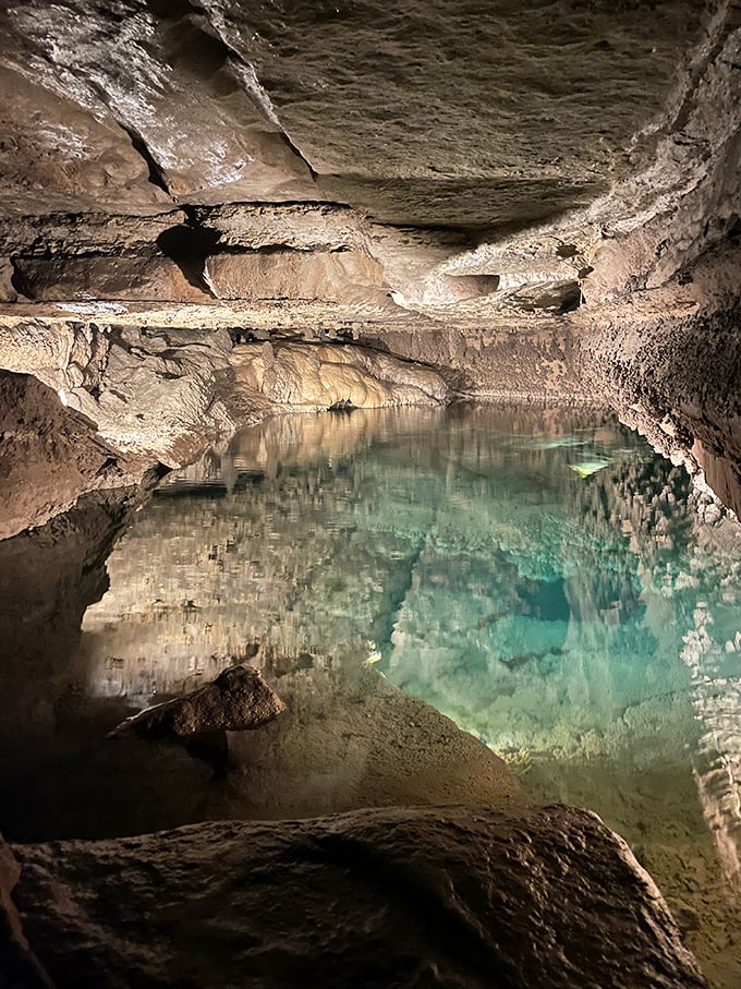 The underground lake glows with an otherworldly turquoise light, its crystal-clear waters reflecting the ancient limestone ceiling above.