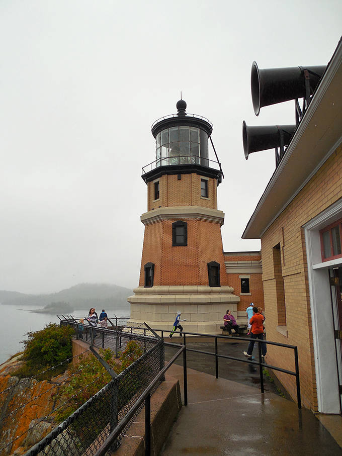 Visitors explore the lighthouse grounds, getting that perfect perspective where history meets breathtaking natural beauty. The pathway offers views that no camera can truly capture.