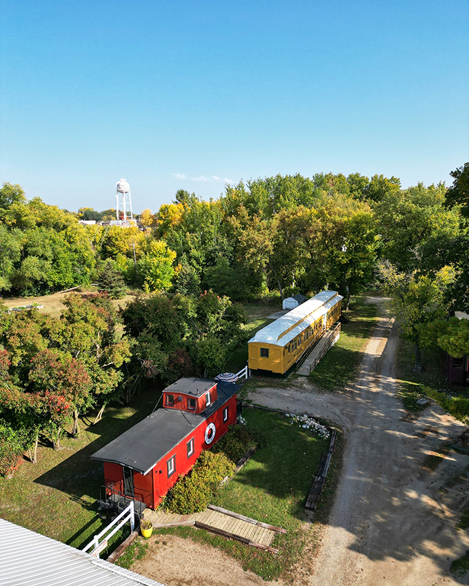 Vintage train cars rest peacefully among autumn foliage, offering a colorful glimpse into the town's railroad heritage.